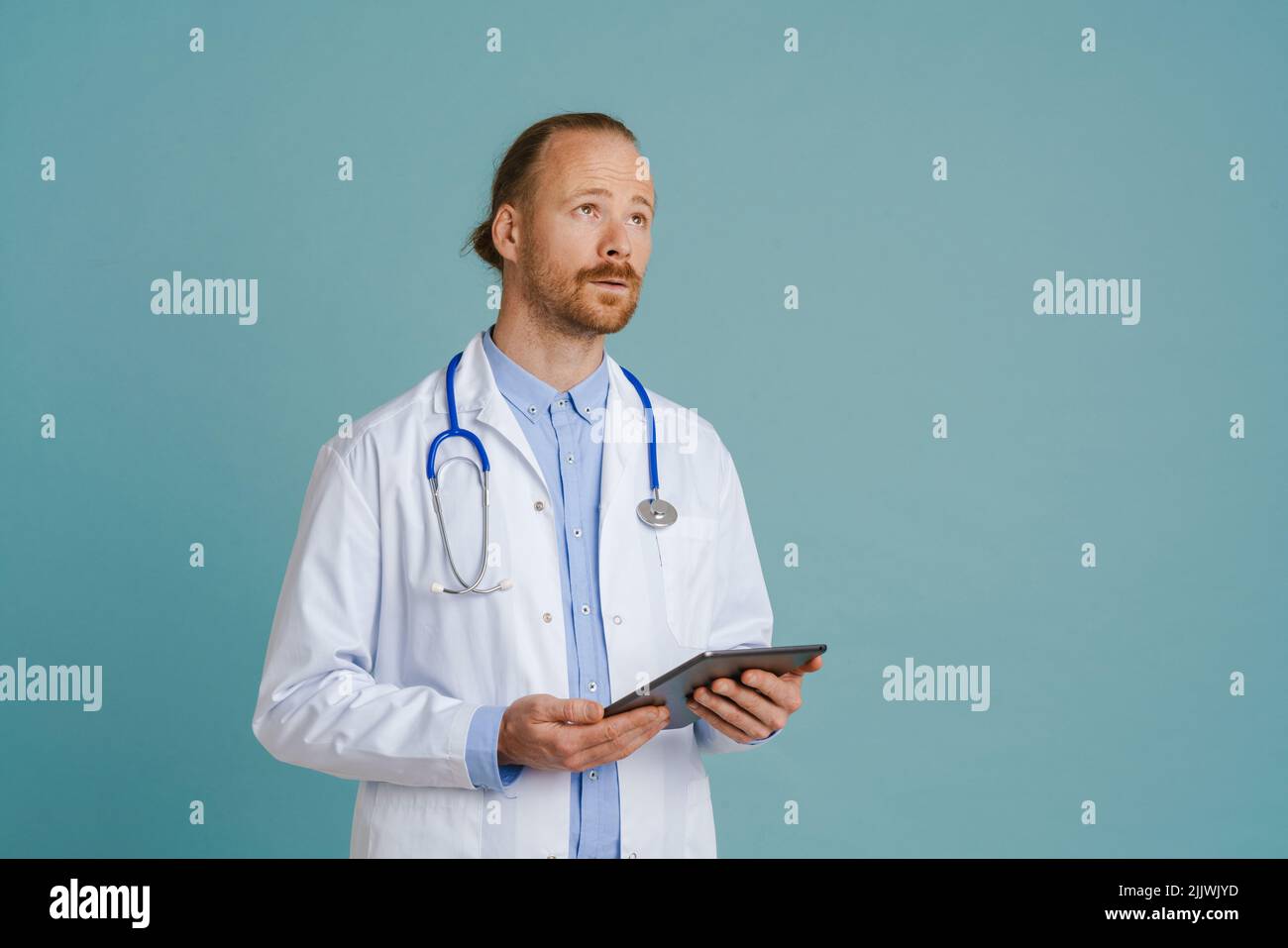 White male doctor wearing lab coat using tablet computer isolated over ...