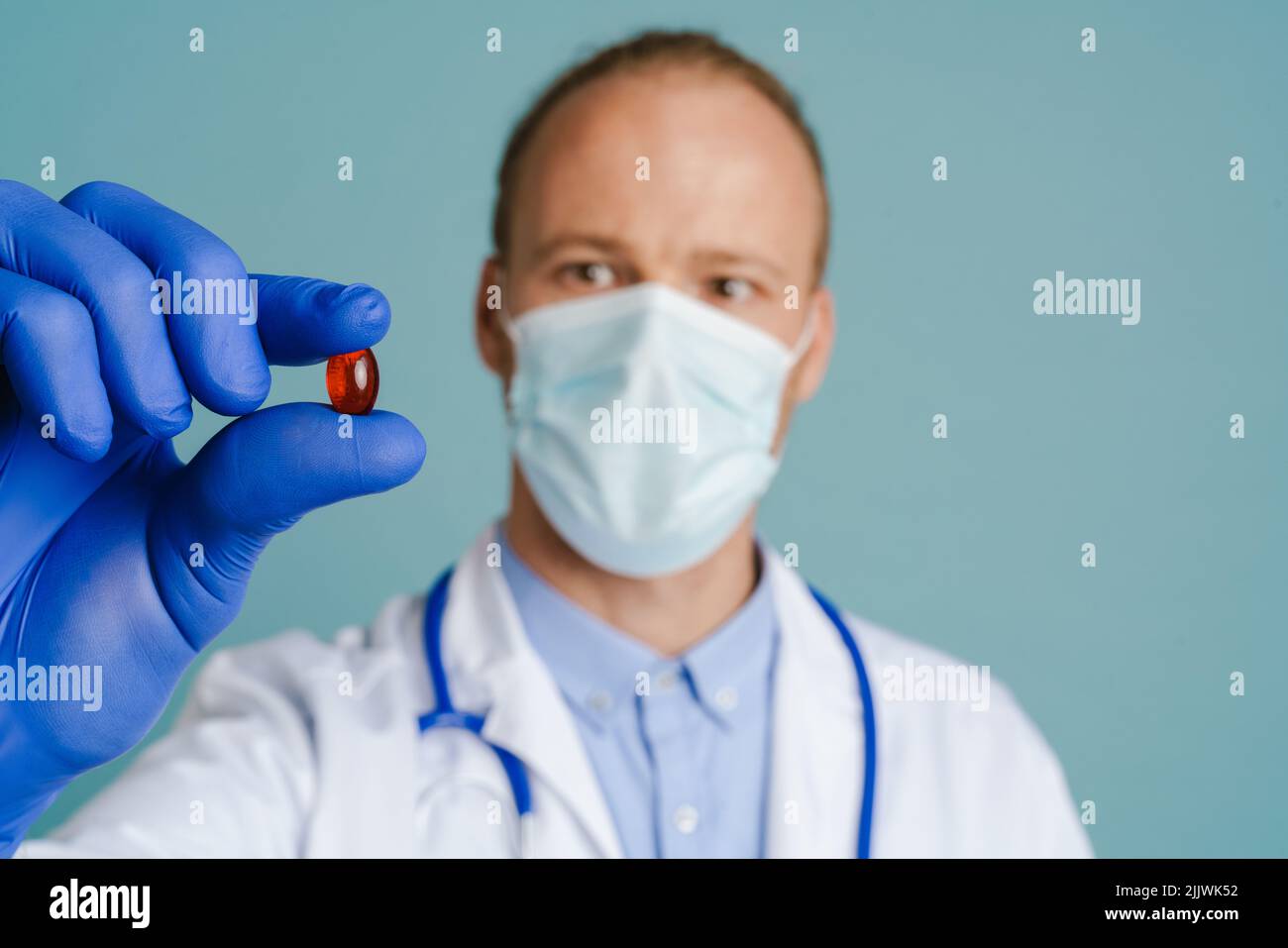 White male doctor wearing face mask showing medicine capsule isolated ...