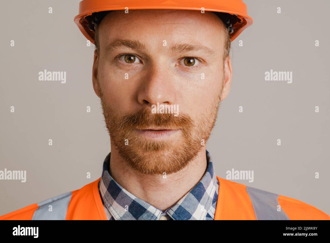 White man worker wearing helmet and vest looking at camera isolated ...