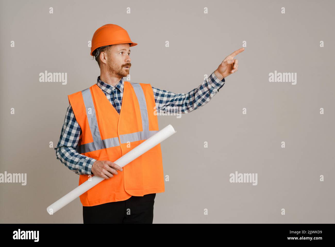 White man builder pointing finger aside while holding drawing isolated ...