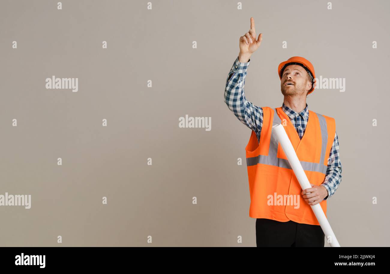 White man builder pointing finger upward while holding drawing isolated ...