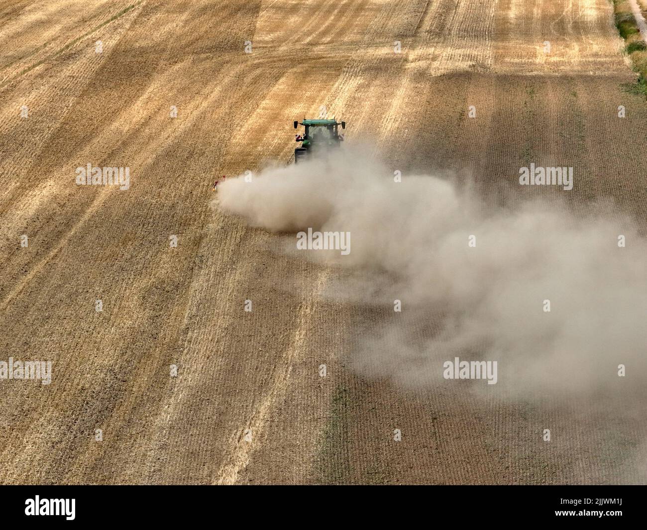 A farmer in his John Deere tractor, with caterpillar tracks, kicks up ...