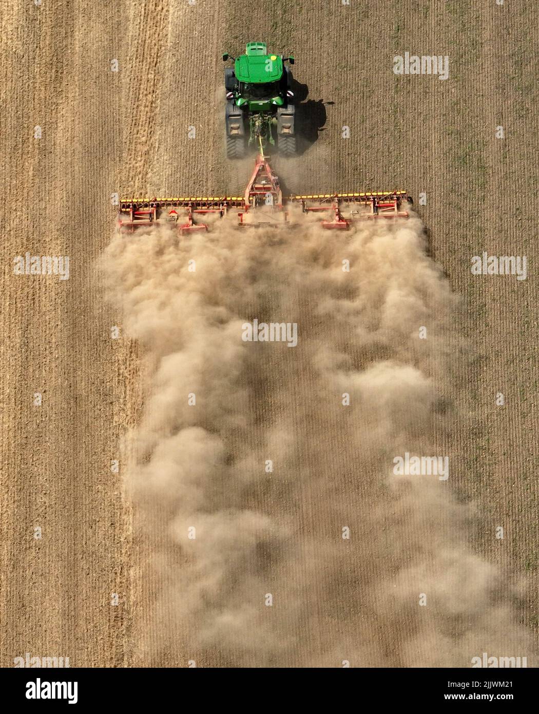 A farmer in his John Deere tractor, with caterpillar tracks, kicks up ...