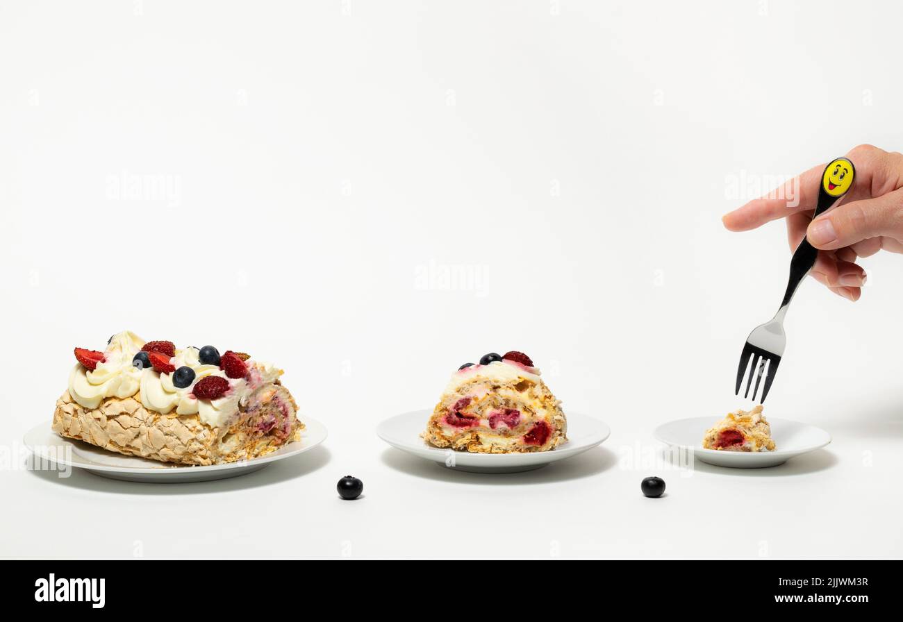 Three different portions of meringue rolls dessert on plates and a hand ...