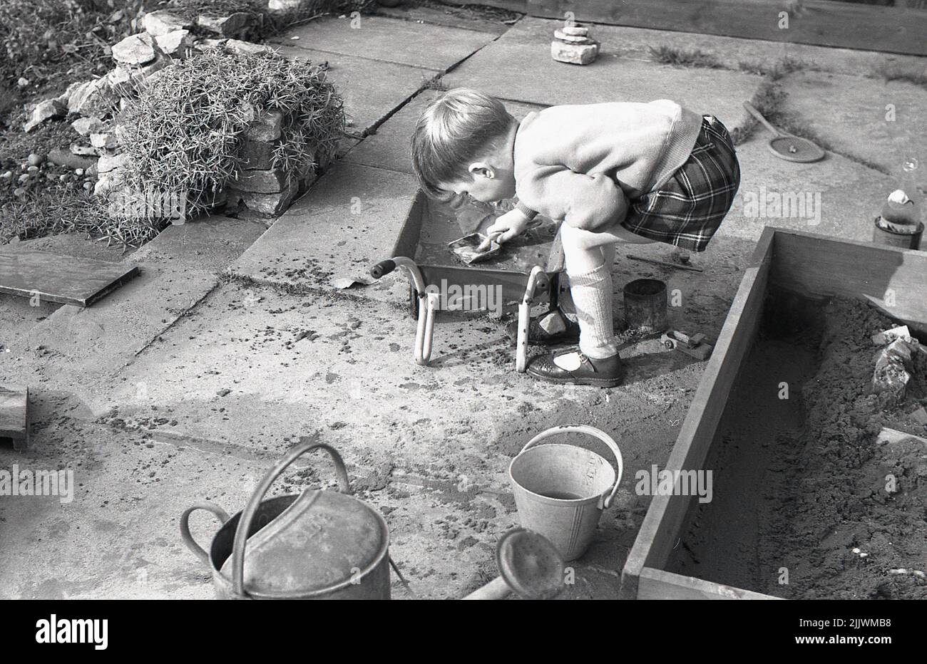 1960s, historical, outside on a patio, a small boy pating down the ...