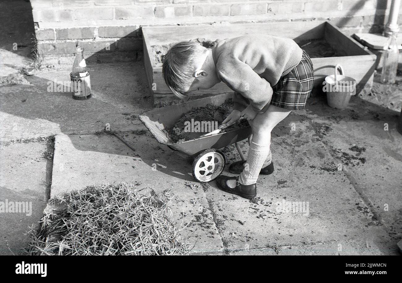 1960s, historical, outside on a patio, a small boy in tartan shorts and ...