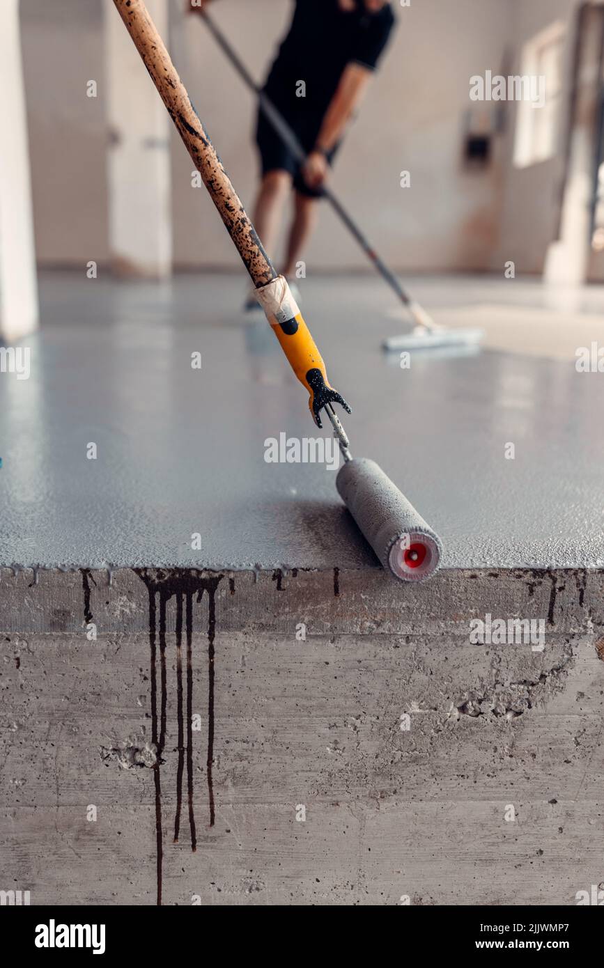 A vertical close up shot of two construction workers applying grey ...