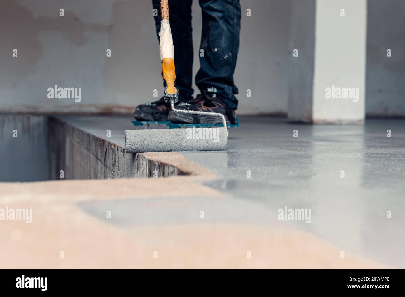 A close up shot of a construction worker applying grey epoxy resin in ...