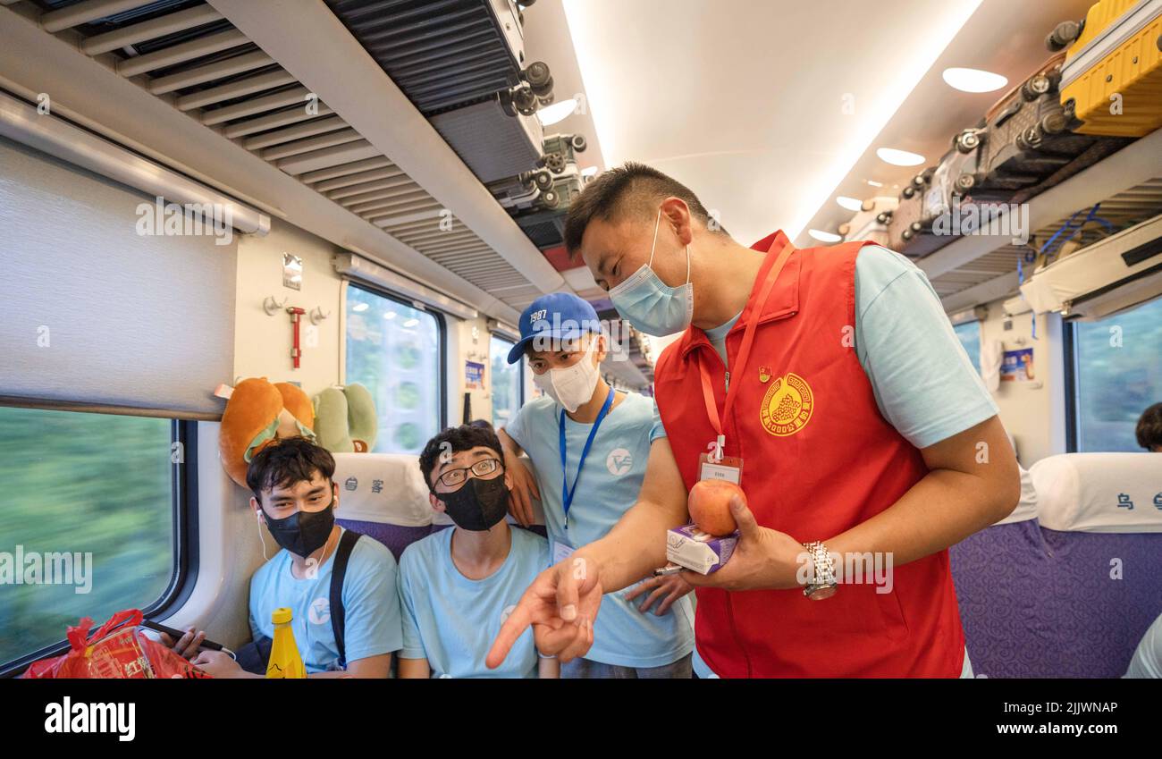 Urumqi. 9th June, 2022. Gu Hailin (1st R) talks with students returning home on train No. K594 ...