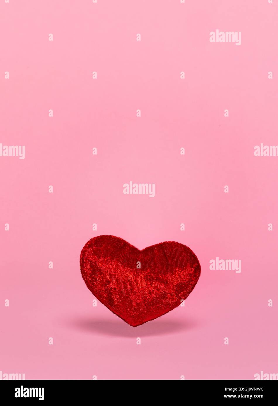 Red velvet fabric heart shaped toy, floating in air. Isolated on a soft ...