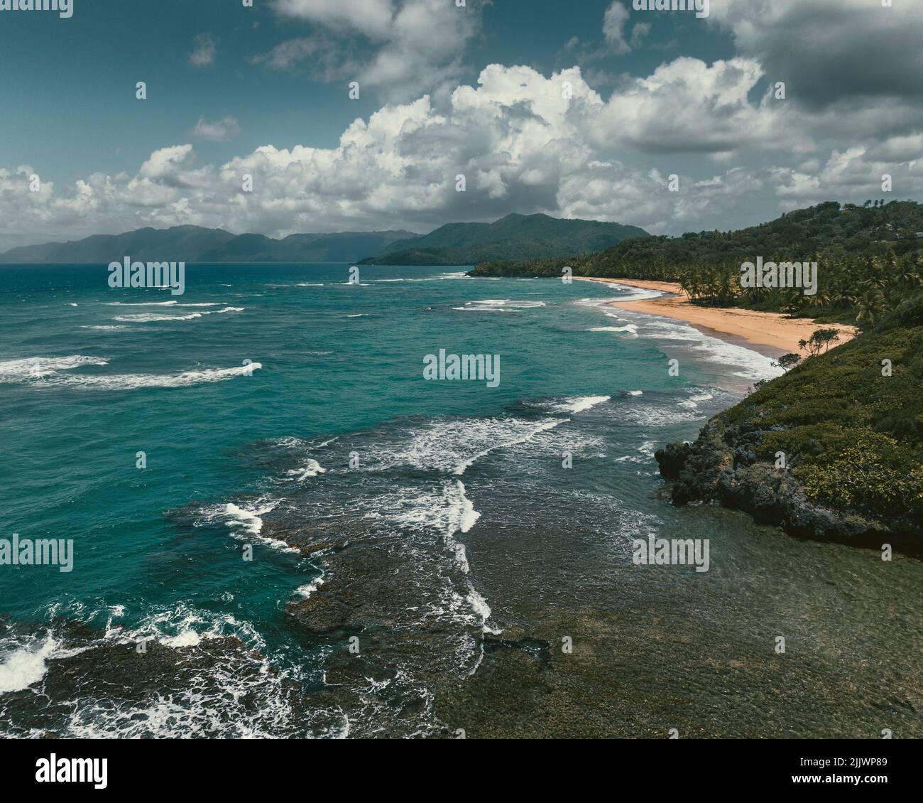 An aerial view of a blue wavy ocean and a cliffy shore during a daytime ...