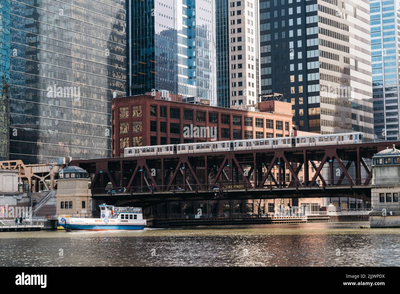 A boat in the river under a train bridge and modern buildings in the ...