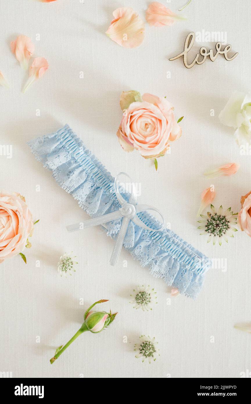 A vertical flat lay of a blue wedding garter and roses Stock Photo - Alamy