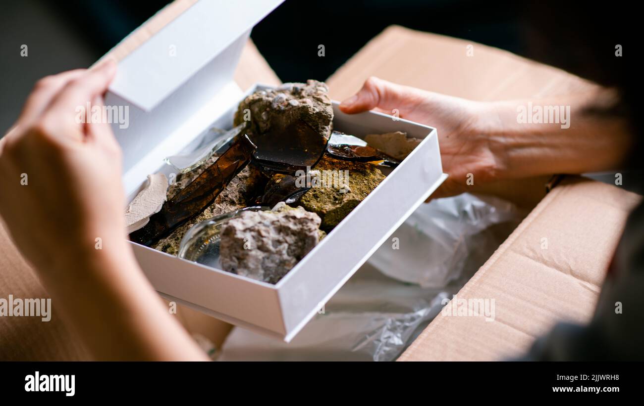 A woman's hand opening a box with broken items Stock Photo - Alamy
