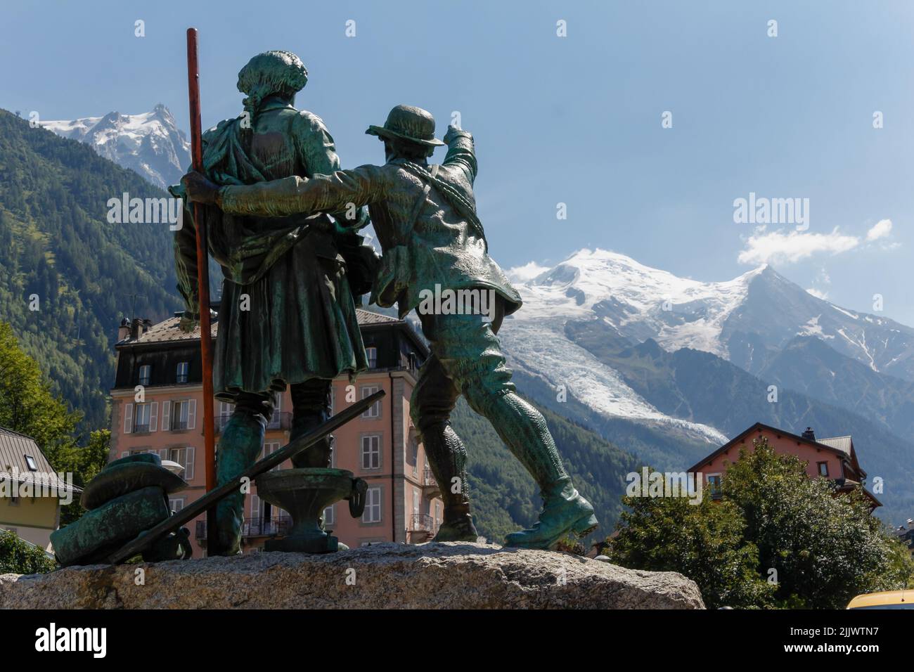 The statue of Balmat and Saussure surrounded by dense trees and rocky ...