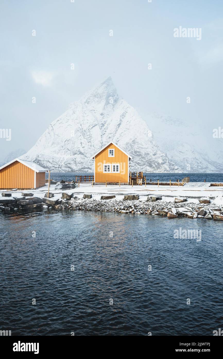 A vertical shot of yellow wooden cabins by the water with the ...