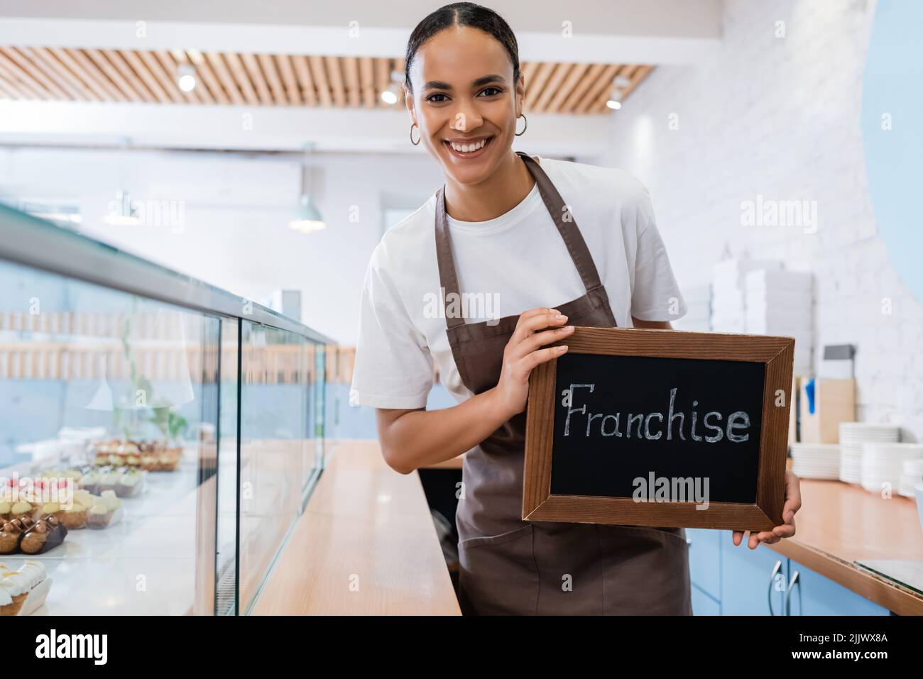 Happy african american saleswoman holding chalkboard with franchise ...