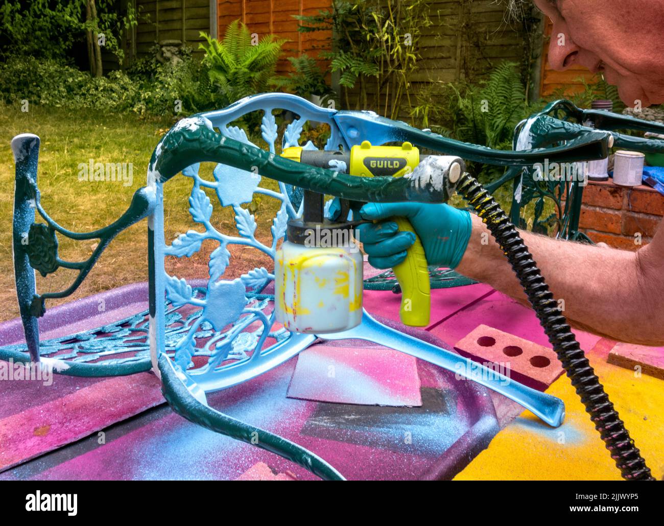 Man using paint spray gun to spray and upcycle wrought iron garden ...