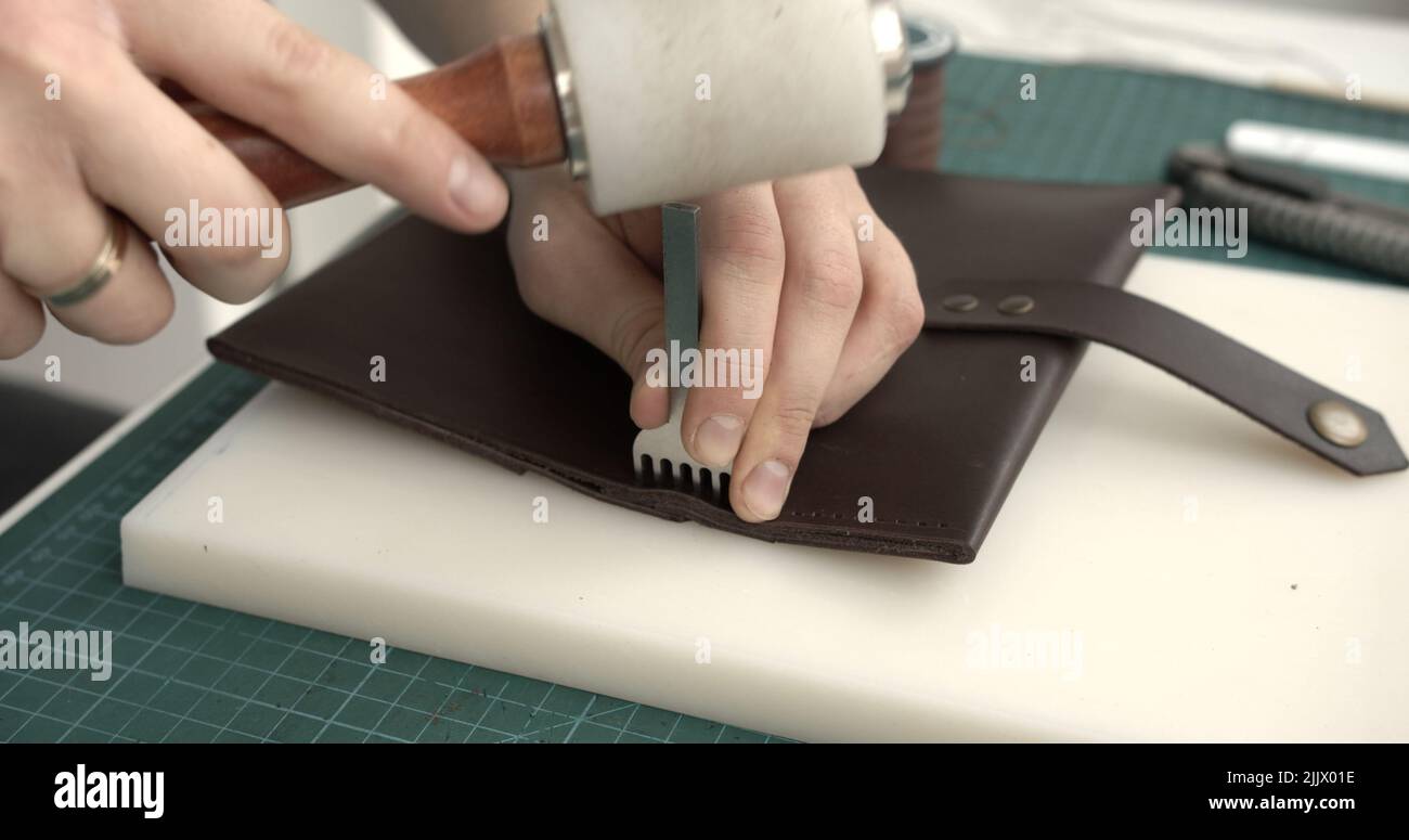 Making of brown handmade leather wallet. Sewing wallet. Piercer punches ...