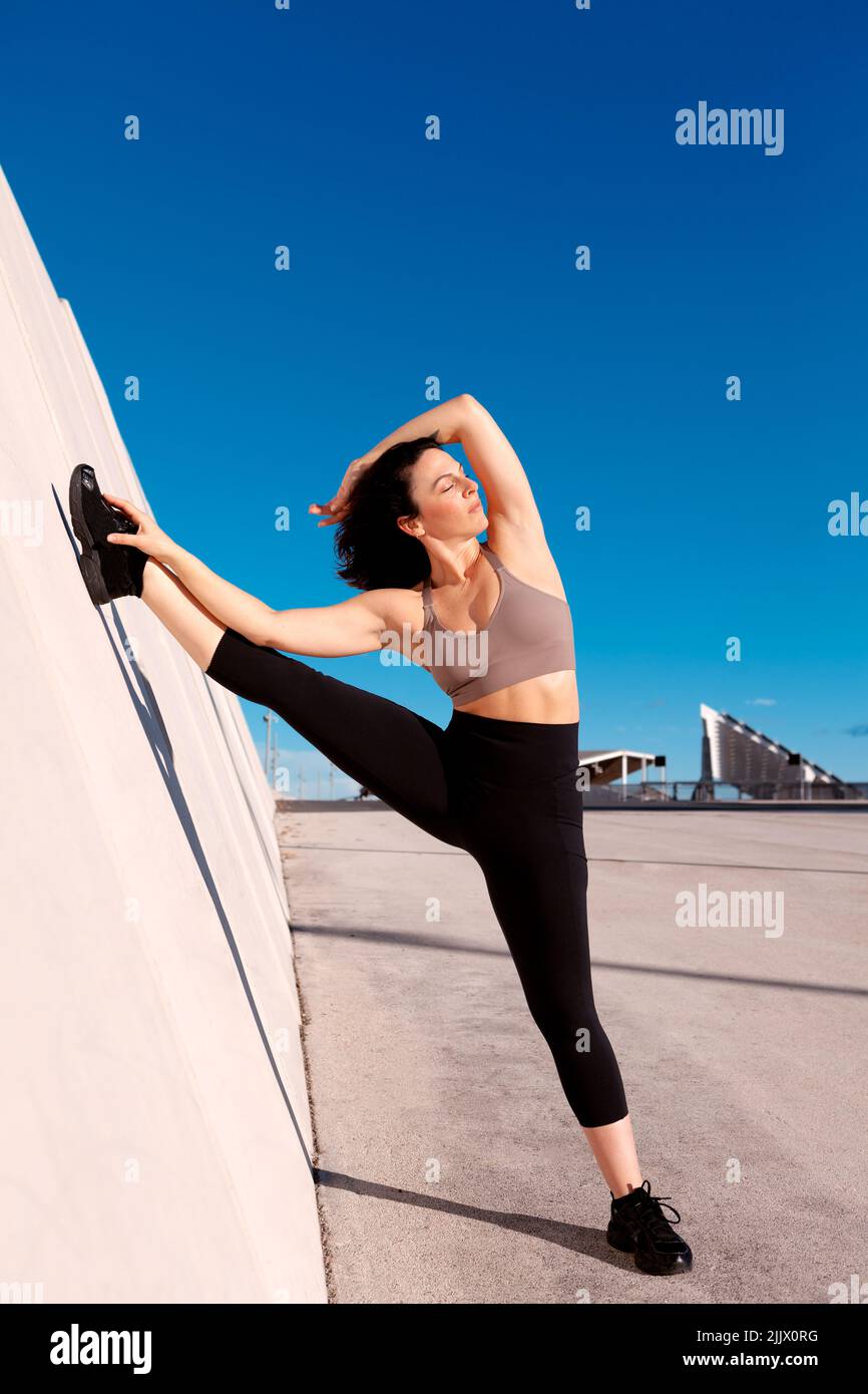 Full body of sporty female in activewear with eyes closed and raised ...