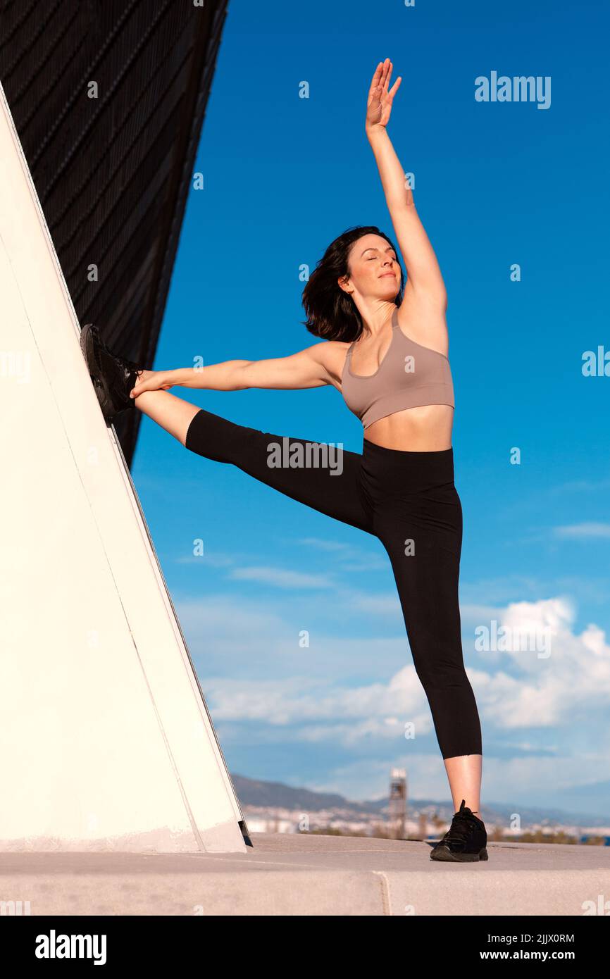 Full body of sporty female in activewear with eyes closed and raised ...
