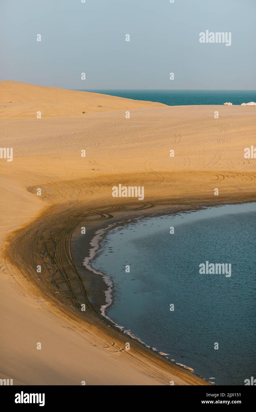 Arid sandy dunes located on shore of sea against blue sky in summer in ...