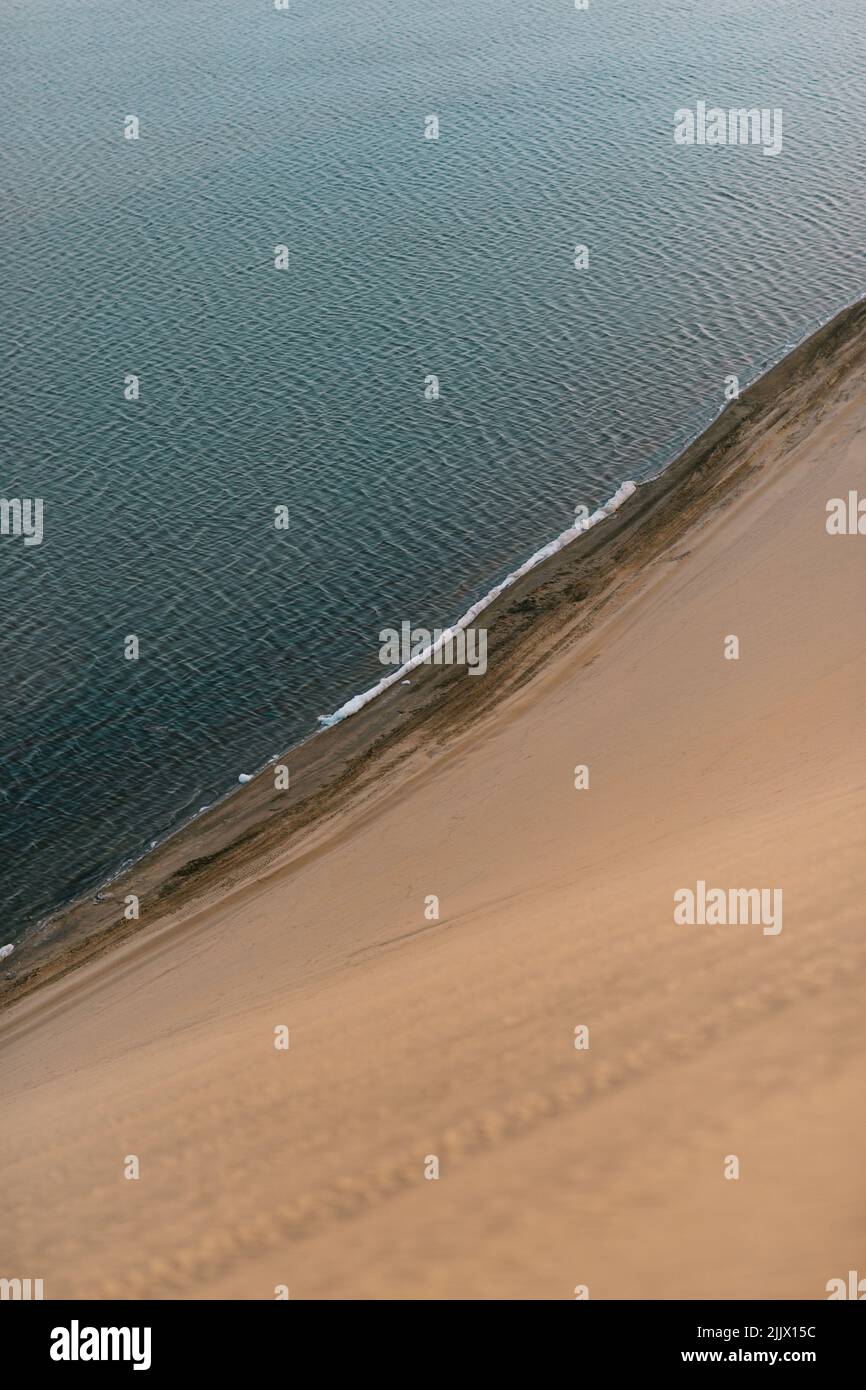 Arid sandy dunes located on shore of sea against blue sky in summer in ...