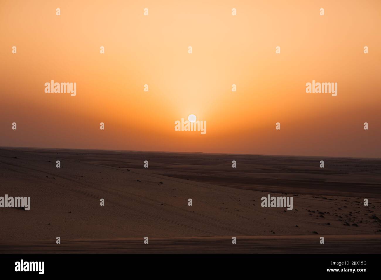 Breathtaking view of bright sundown sky with orange sun over arid ...