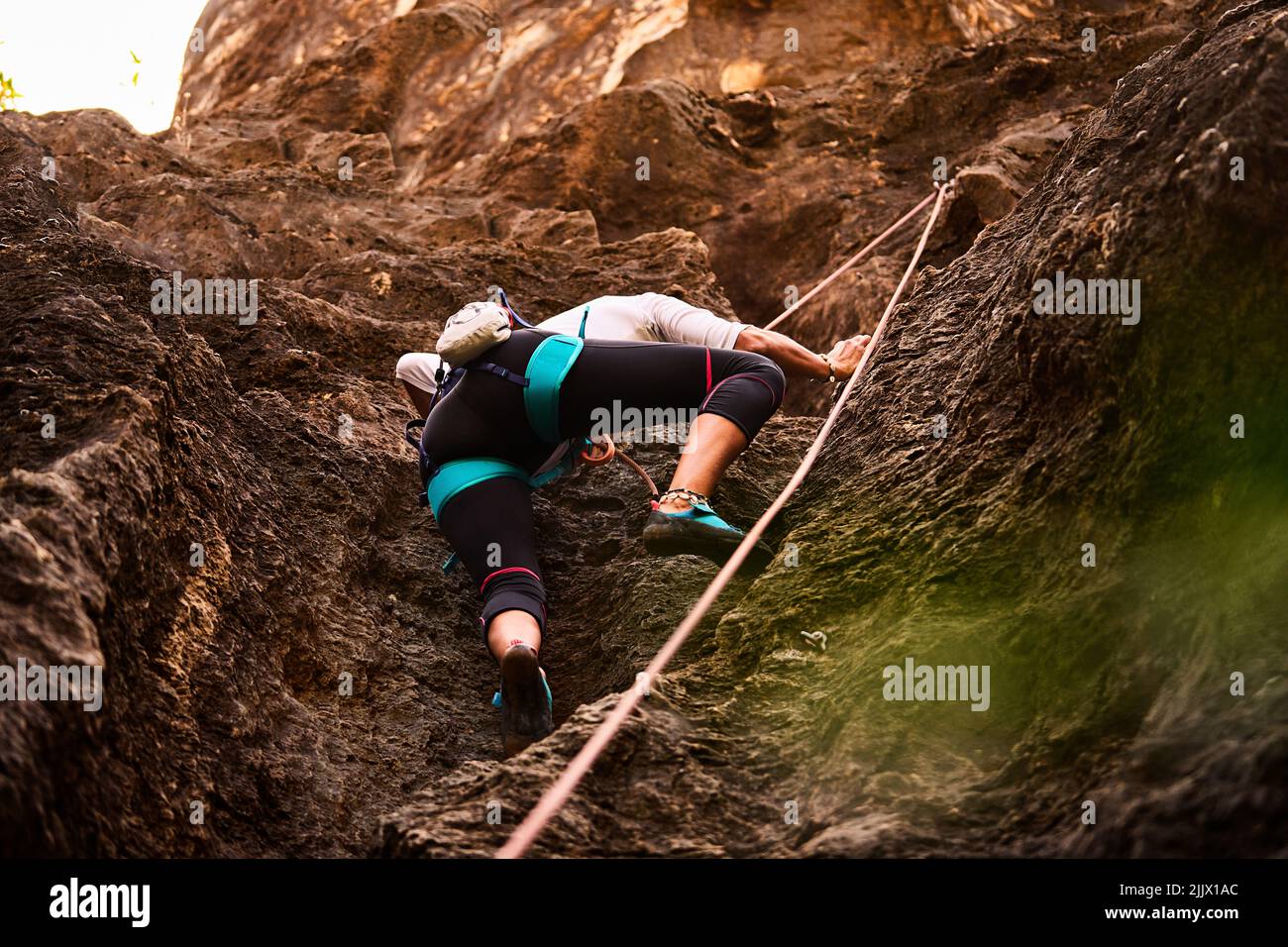 Low angle full body of active man climbing on rocky cliff Stock Photo ...
