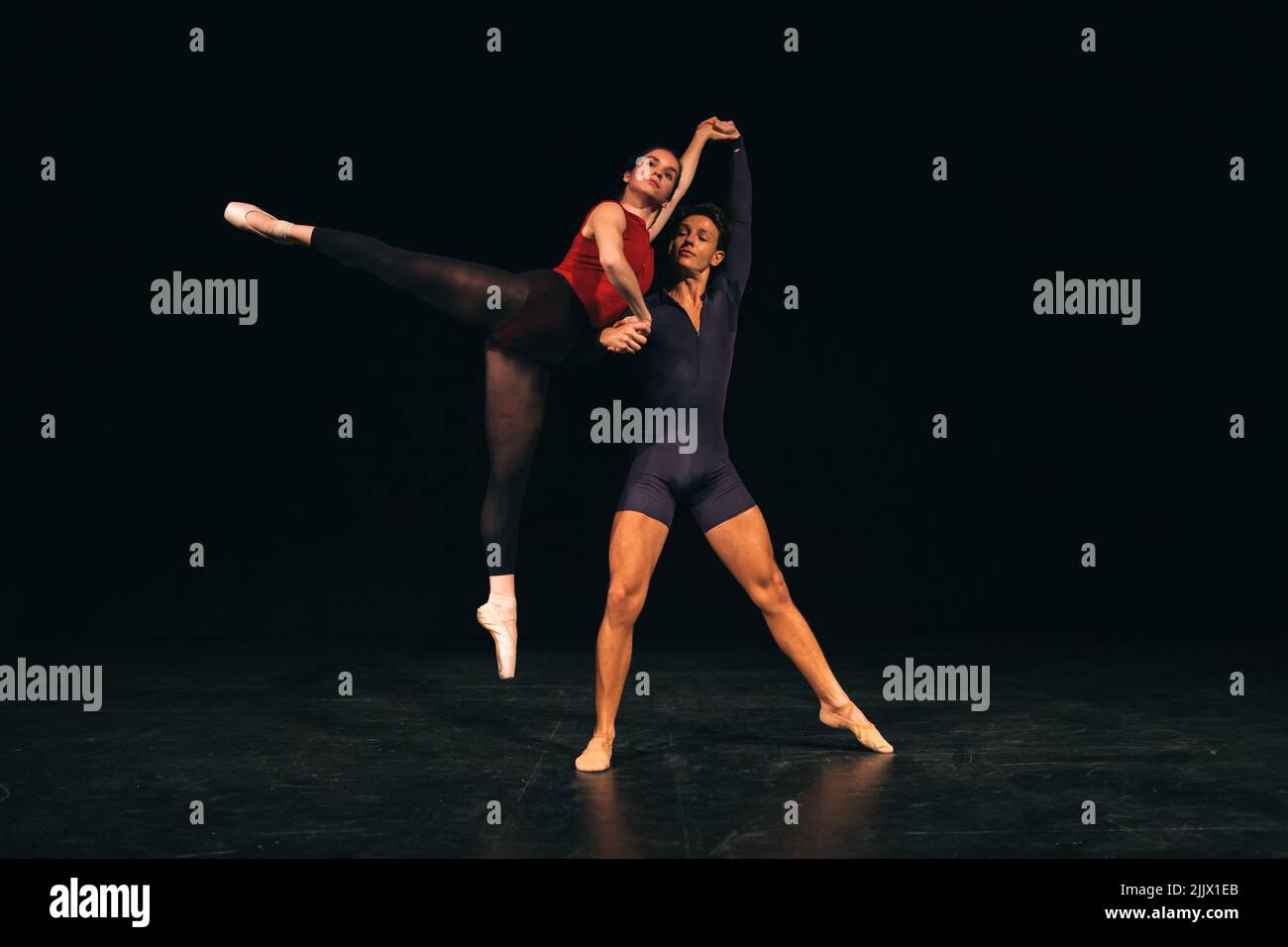 Full body danseur lifting ballerina while dancing on dark stage during ...