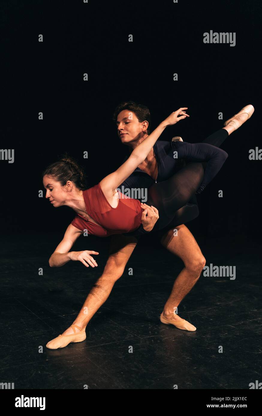 Full body danseur lifting ballerina while dancing on dark stage during ...