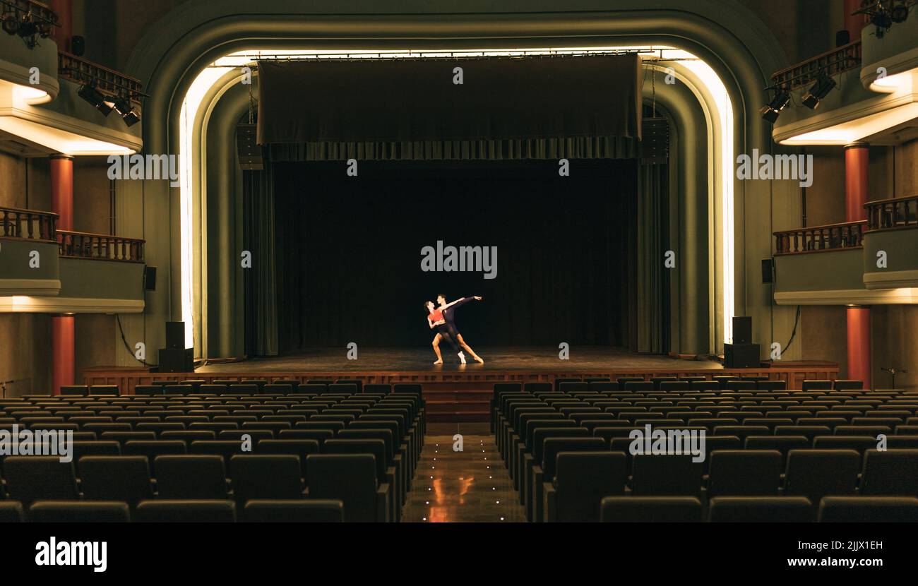 man and Woman dancing together on stage near empty seats during ...