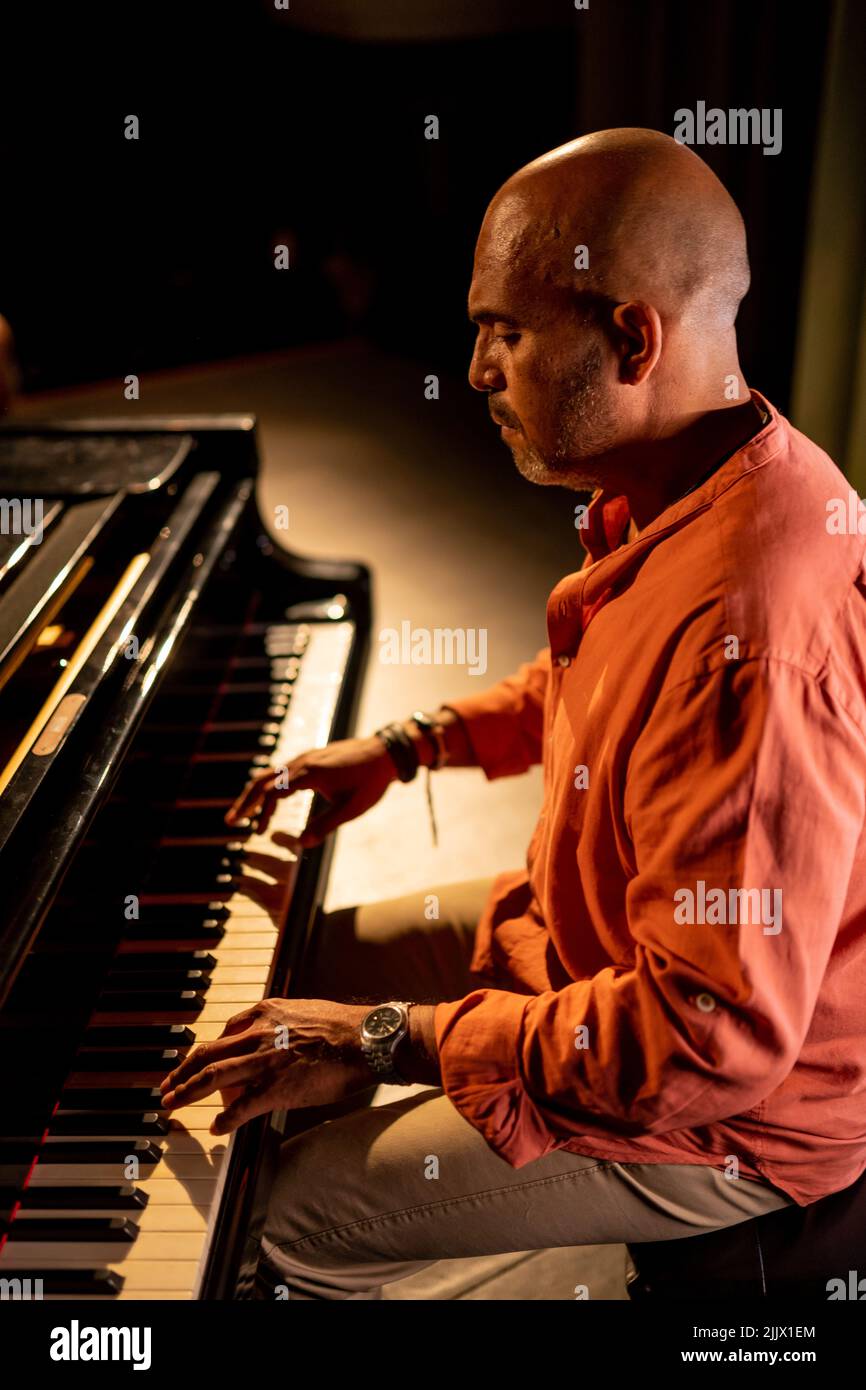 Side view of focus bald male musician playing piano during performance ...