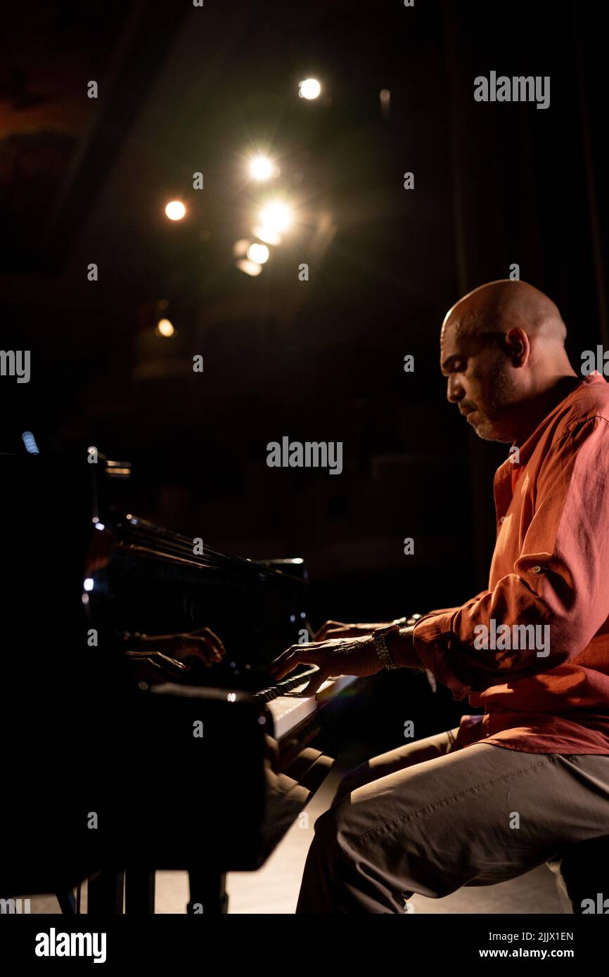 Side view of focus bald male musician playing piano during performance ...