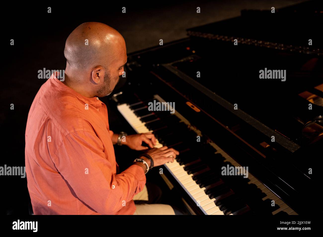 Side view of focus bald male musician playing piano during performance ...