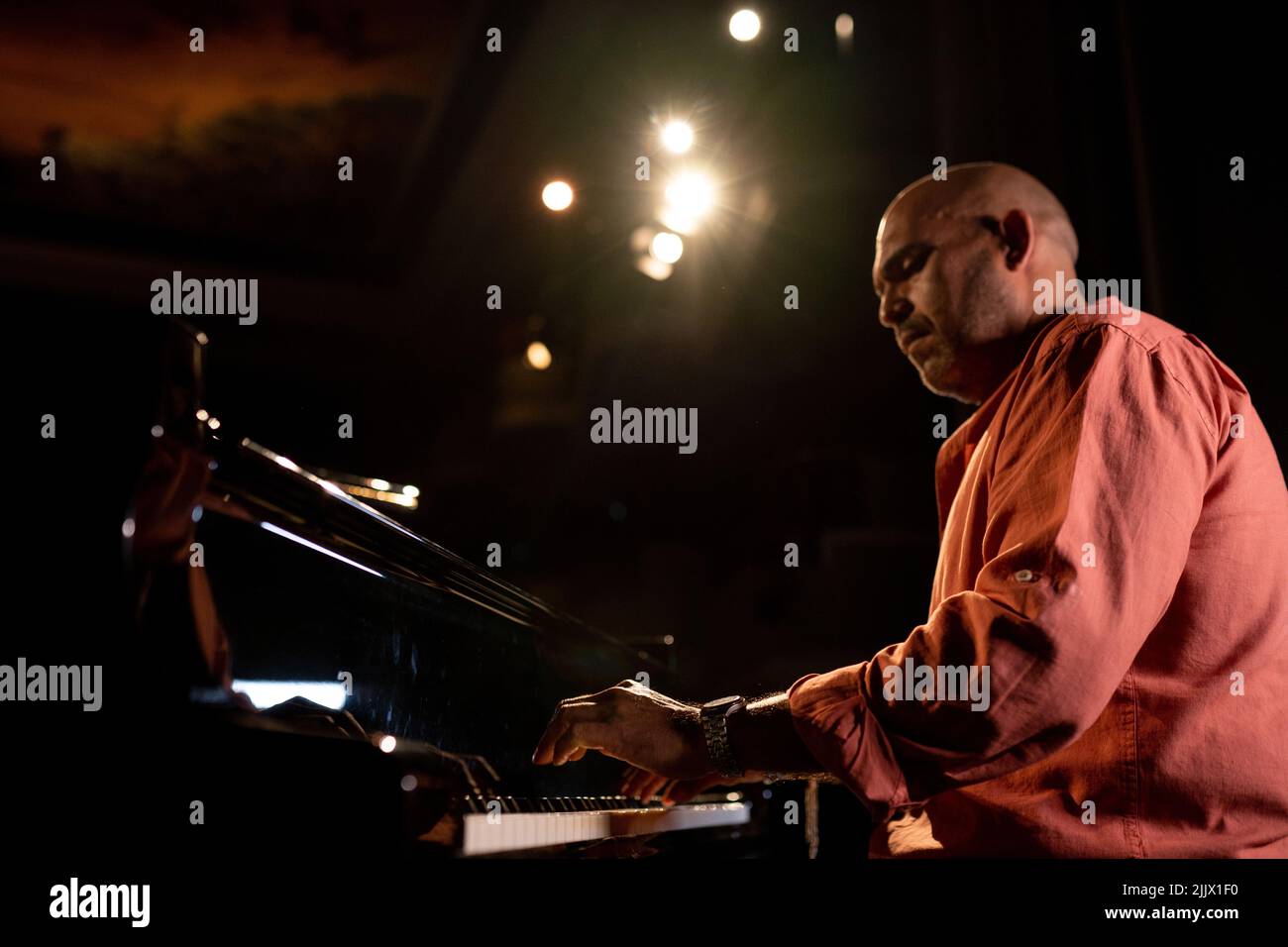 From below side view of bald male musician playing piano during ...