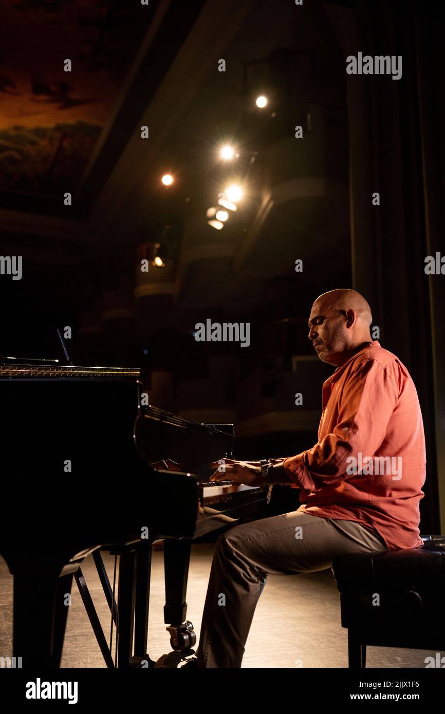 Side view of focus bald male musician playing piano during performance ...