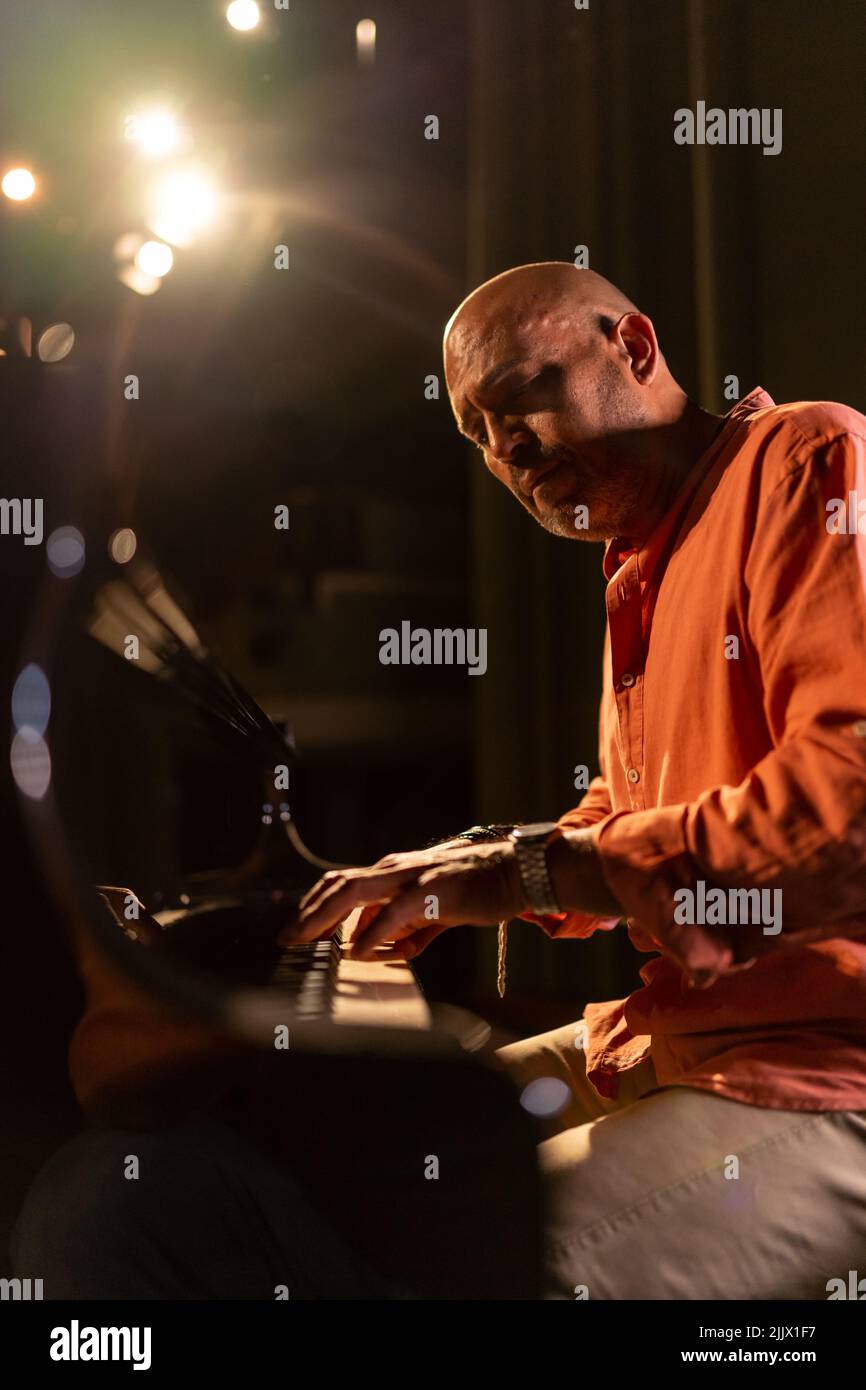 From below side view of bald male musician playing piano during ...