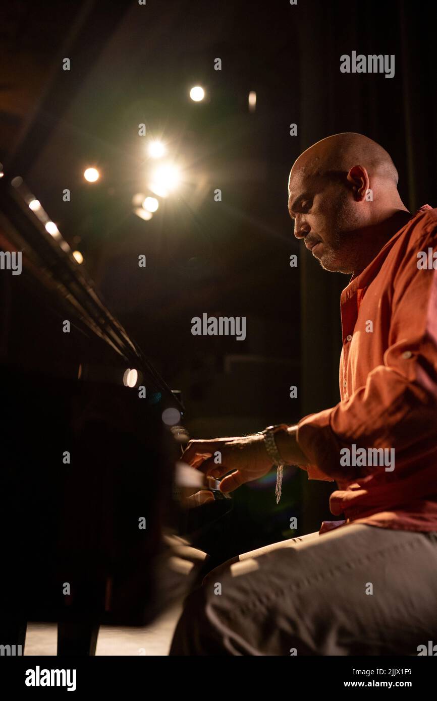 From below side view of bald male musician playing piano during ...