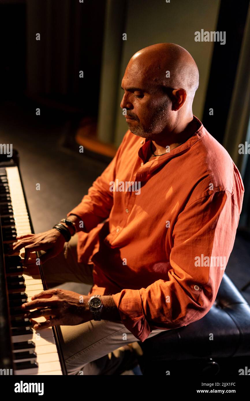 Side view of focus bald male musician playing piano during performance ...
