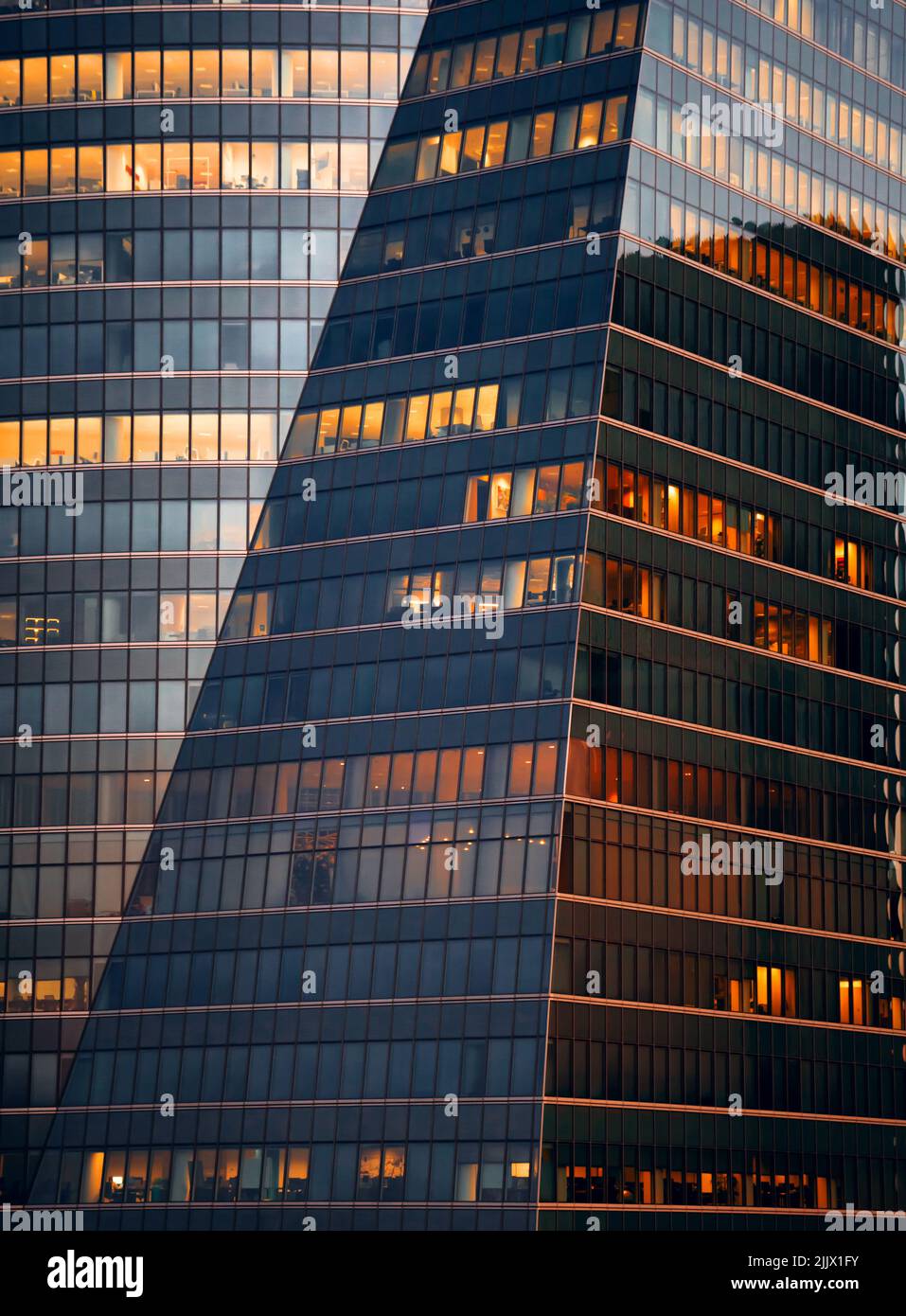 Low angle of modern geometric high office building by night with dense ...