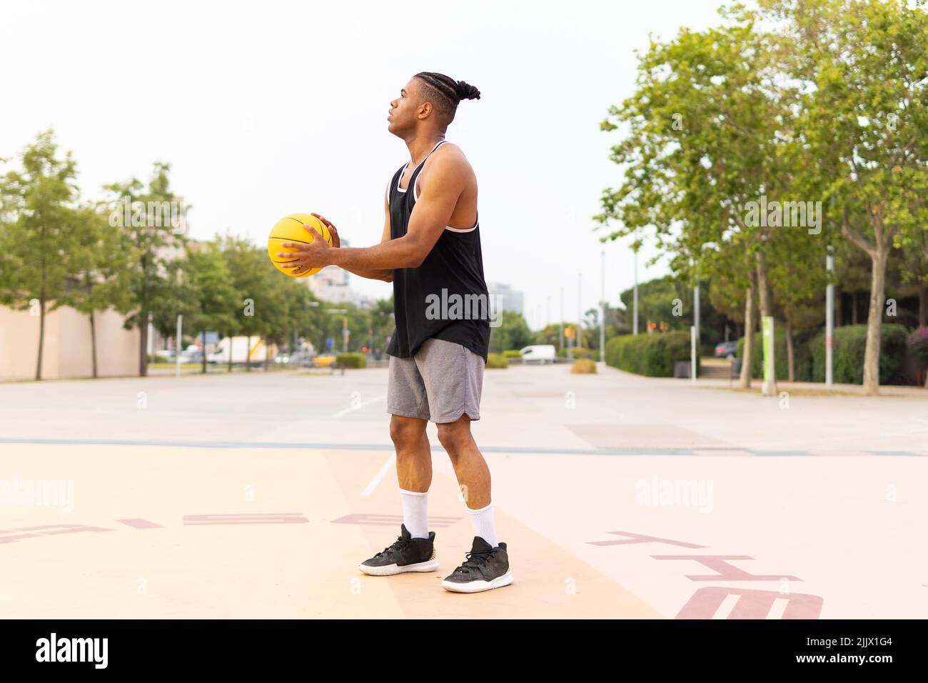 Full body Hispanic male athlete with hair bun bouncing yellow ball ...