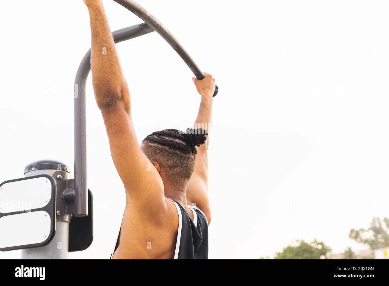 Low angle side view of unrecognizable Hispanic male athlete doing pull ...