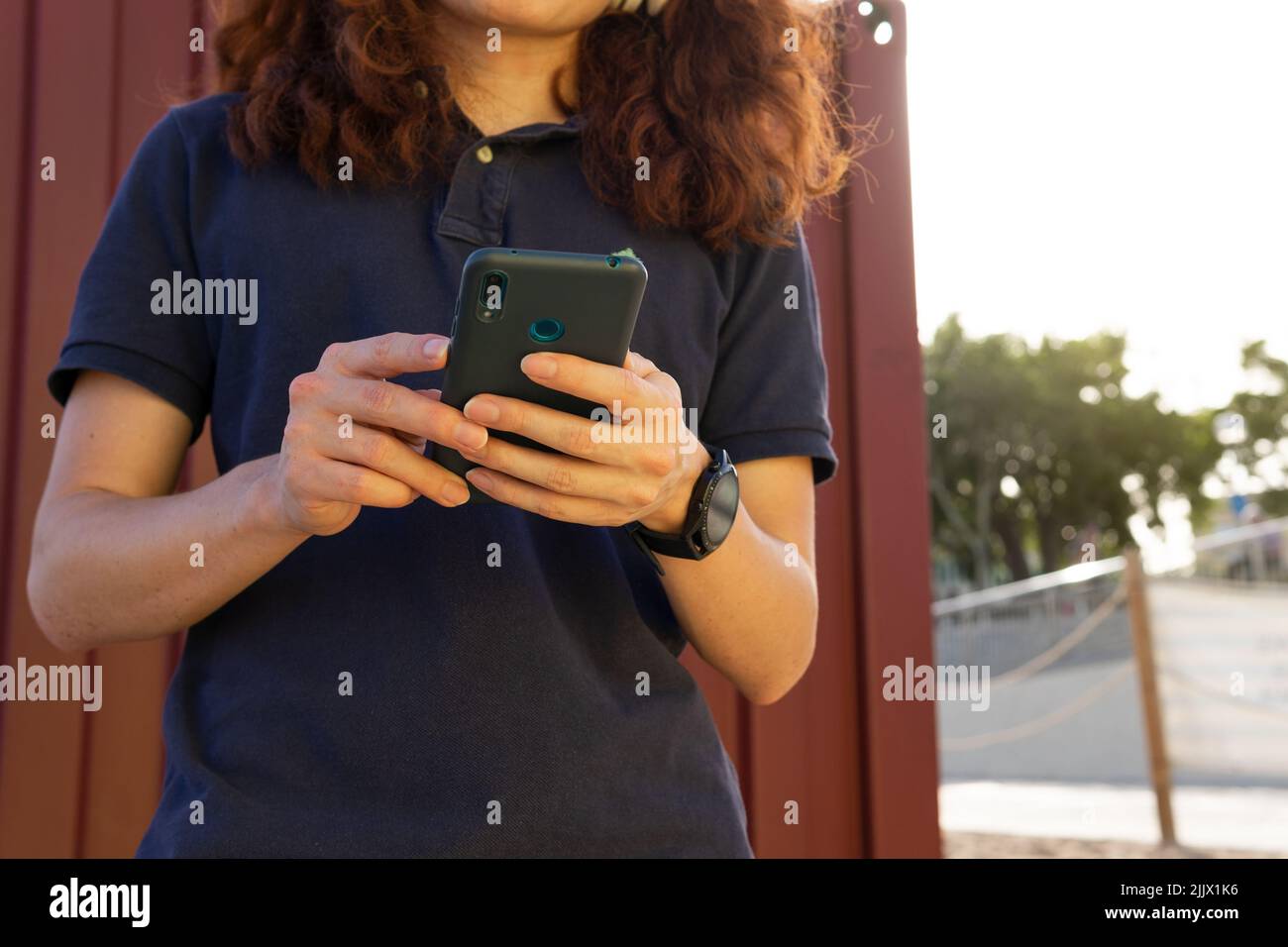 Anonymous young Woman browsing through smartphone against metallic wall ...