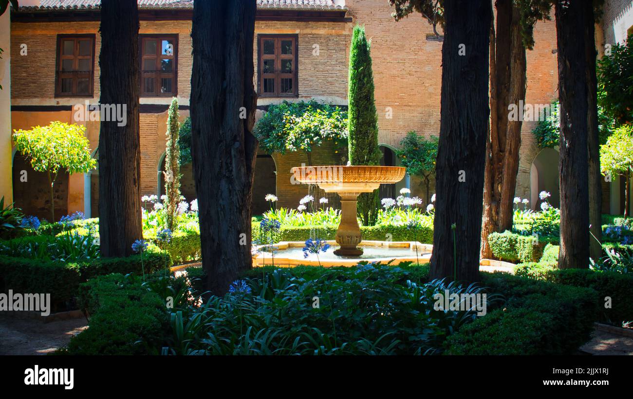The immaculate garden of Alhambra Palace with trees and a water ...