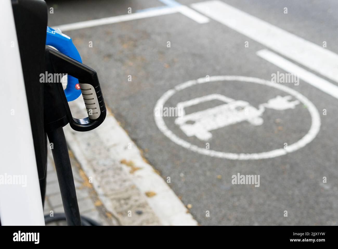 White sign of electric automobile charging on asphalt road at car ...