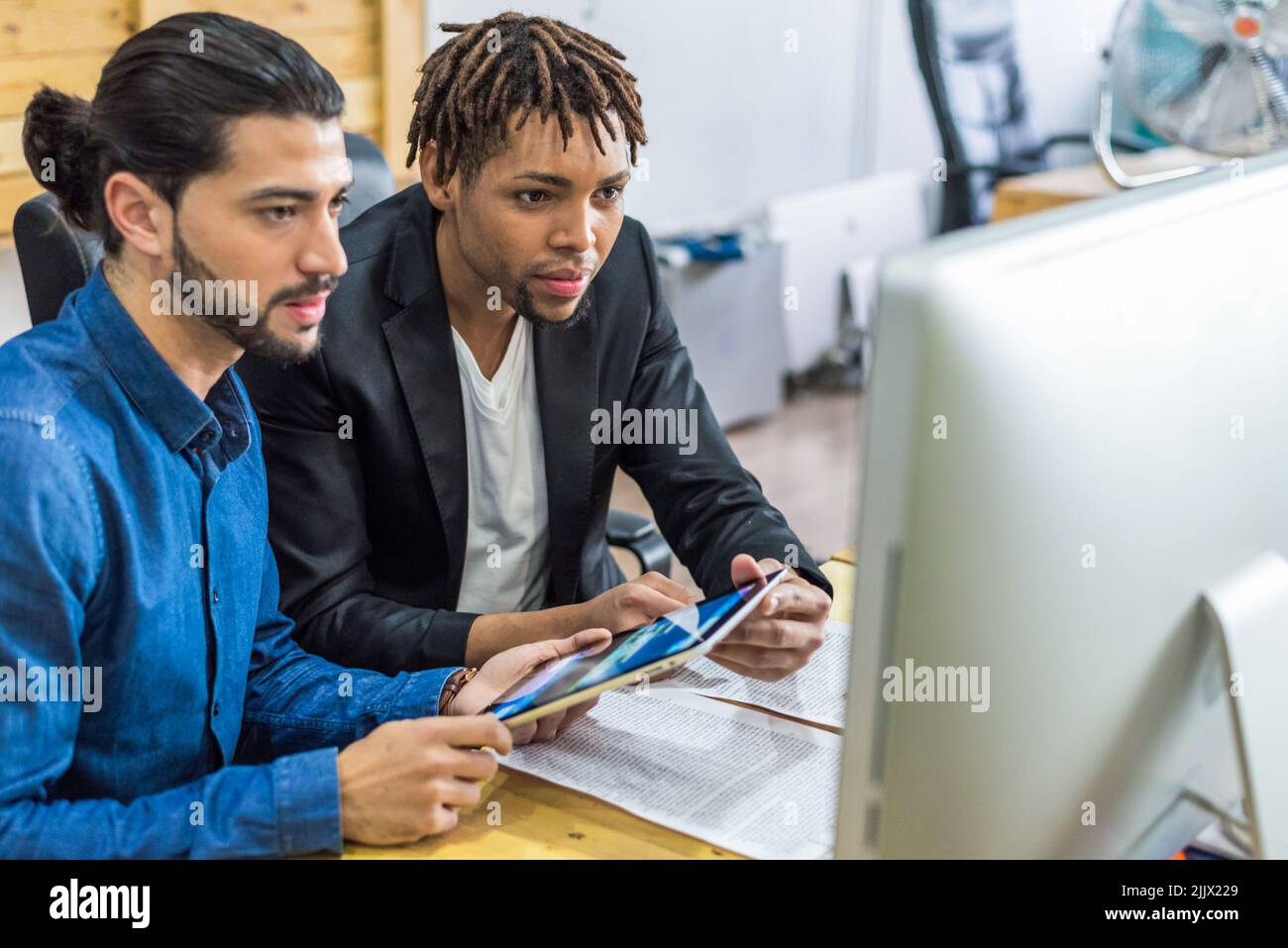 Glad diverse male employees in formal wear surfing tablet while working ...