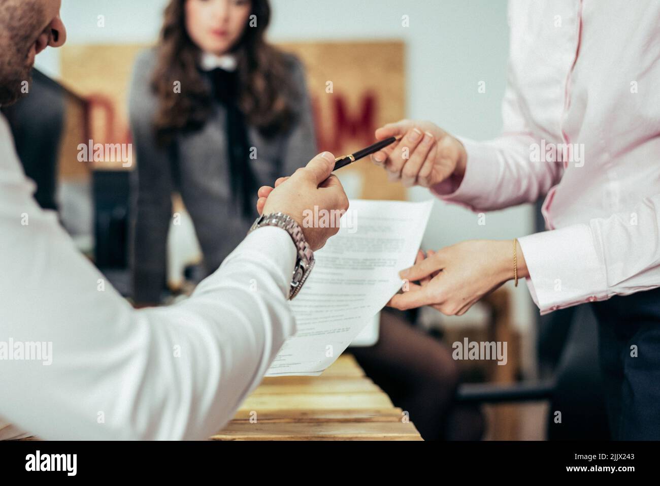 Crop anonymous worker in formal wear taking pen from faceless colleague ...