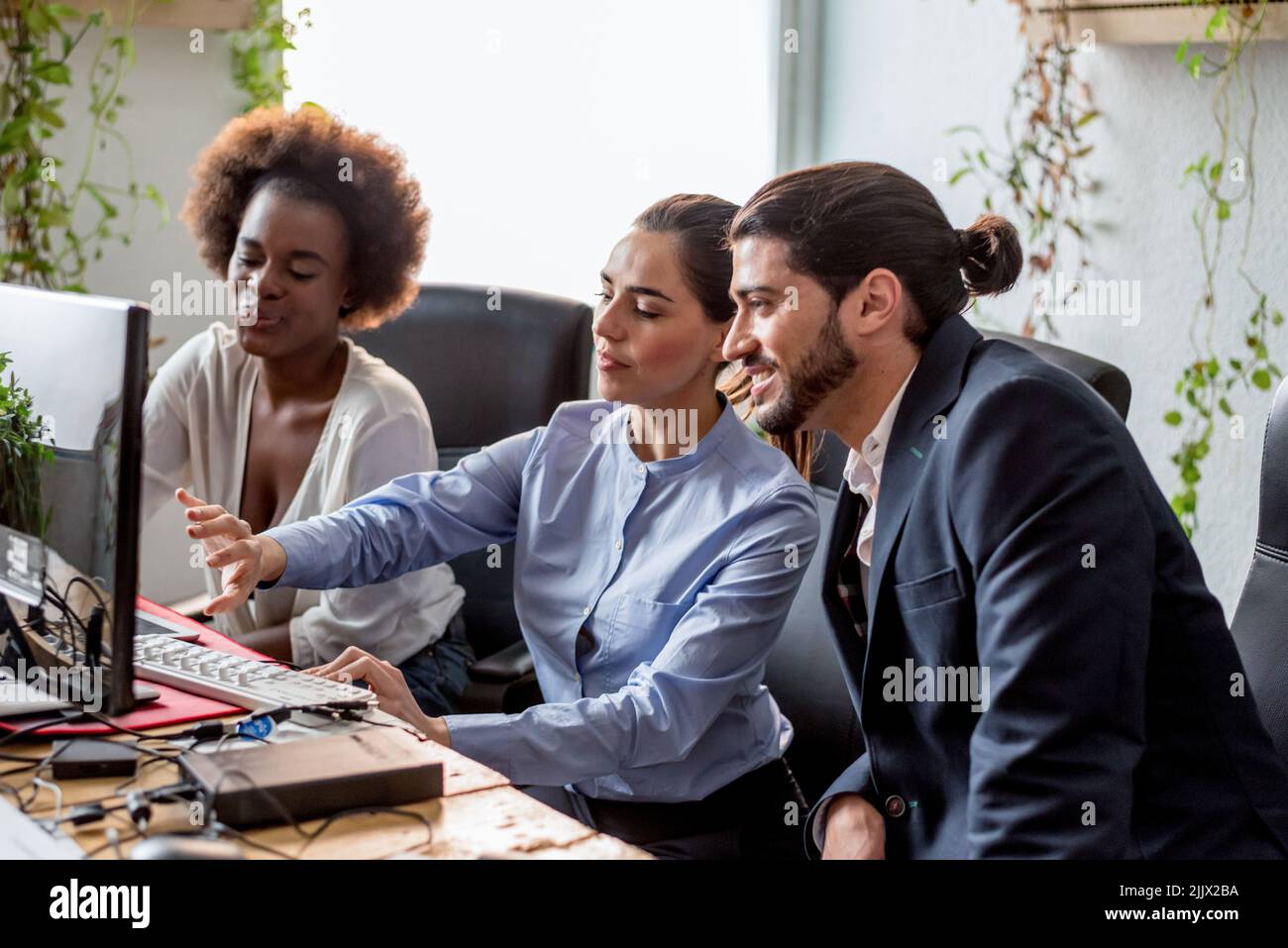 Group of content multiracial coworkers in formal wear surfing internet on computer while working ...