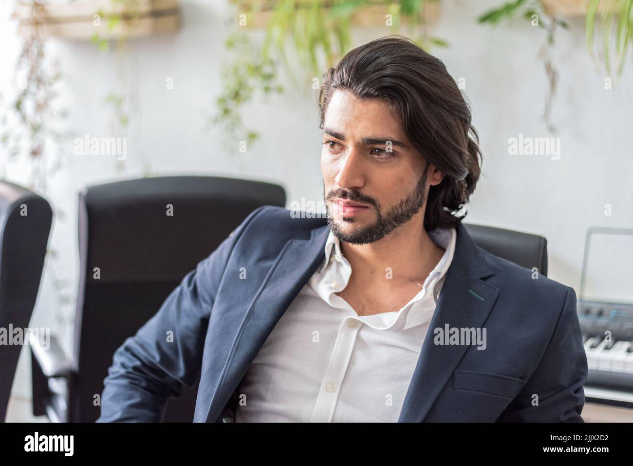 Confident beaded male manager in formal suit looking away while sitting ...